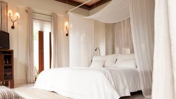 Quarto com uma cama grande, televisão em um armário de madeira e janela com cortinas.