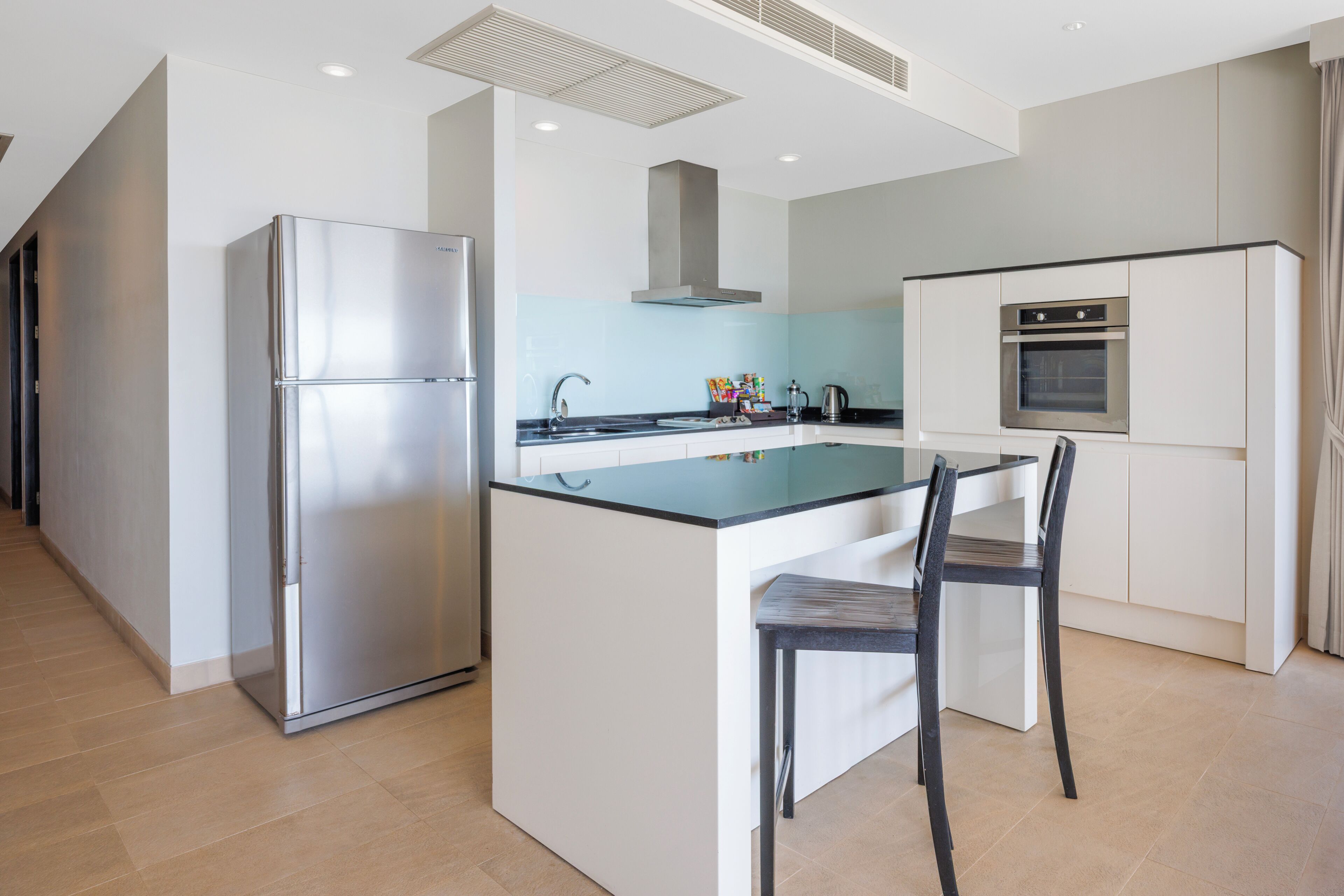 Uma cozinha moderna com ilha central, eletrodomésticos de aço inoxidável e forno embutido.