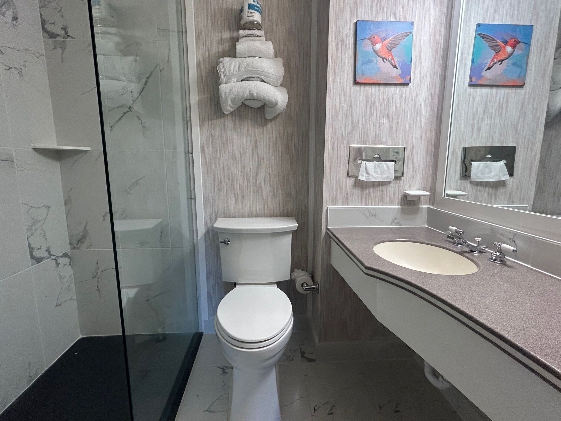 Uma casa de banho moderna com sanita, lavatório e cabine de duche em vidro.