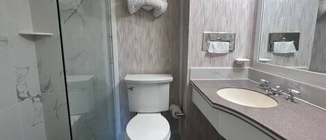 Uma casa de banho moderna com sanita, lavatório e cabine de duche em vidro.