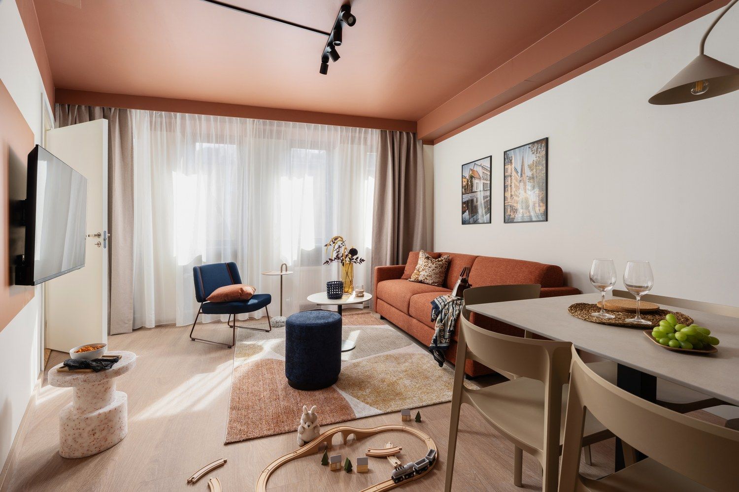Uma sala de estar moderna com sofá, mesa de jantar e televisão.