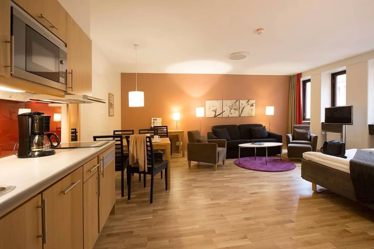 Quarto de hotel moderno com cozinha compacta, área de refeições e espaço para sentar.