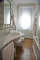 Uma casa de banho moderna com um espelho grande, uma pia, sanita e zona de duche.