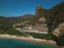 Um resort costeiro com vários edifícios de hotel, uma praia e um cenário montanhoso.