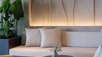 Uma sala de estar moderna com um sofá, duas poltronas, uma mesa de centro e uma luminária pendente.