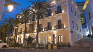 Um hotel com várias andares, varandas, palmeiras e áreas de estar ao ar livre.