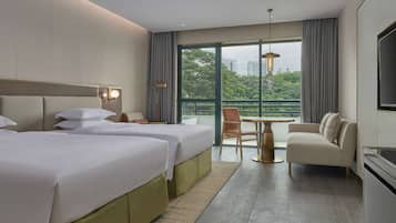 Quarto de hotel com duas camas, um sofá, uma mesa de jantar e uma televisão.