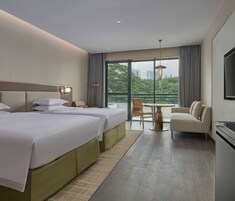 Quarto de hotel com duas camas, um sofá, uma mesa de jantar e uma televisão.