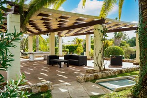 Um pátio coberto ao ar livre com pérgola, área de estar e uma pequena piscina.