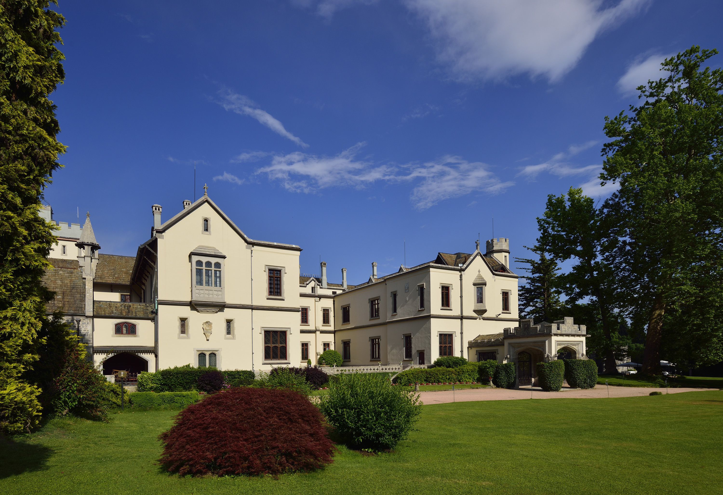 Um edifício grande e histórico com várias alas e um jardim bem cuidado.