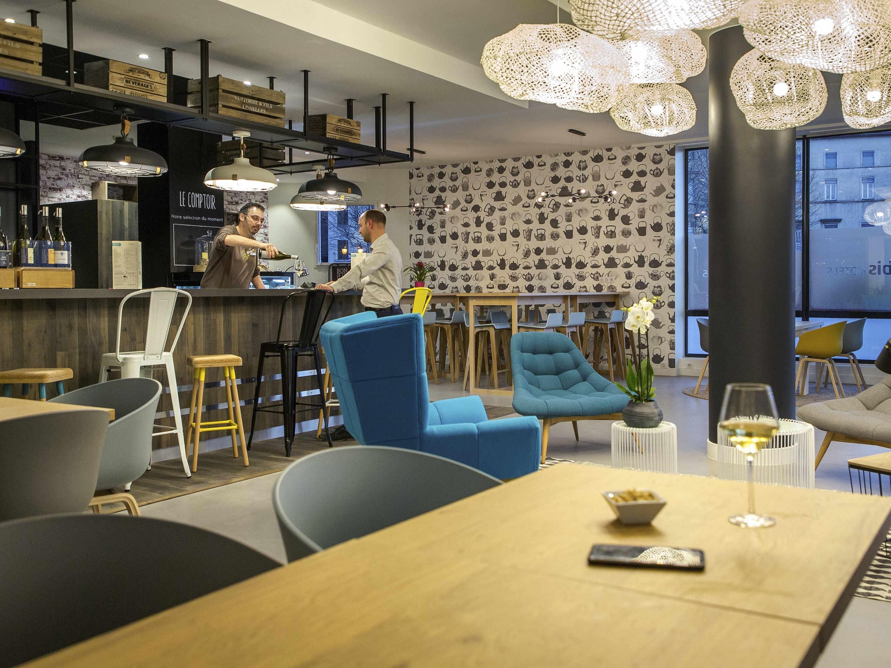 Uma área de bar moderna com balcão, banquetas e um espaço de estar com cadeiras e mesas.
