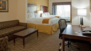 Quarto de hotel com duas camas, um sofá, uma escrivaninha e uma cadeira.