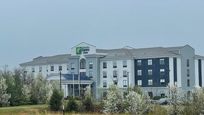 Um hotel Holiday Inn Express com entrada central, vários andares e um estacionamento em primeiro plano.