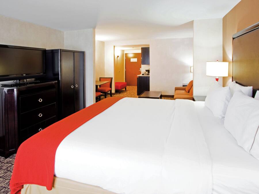 Quarto de hotel com cama grande, televisão, escrivaninha e uma cadeira.