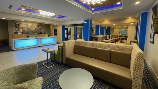 Um saguão de hotel com balcão de recepção, área de estar e espaço para refeições.