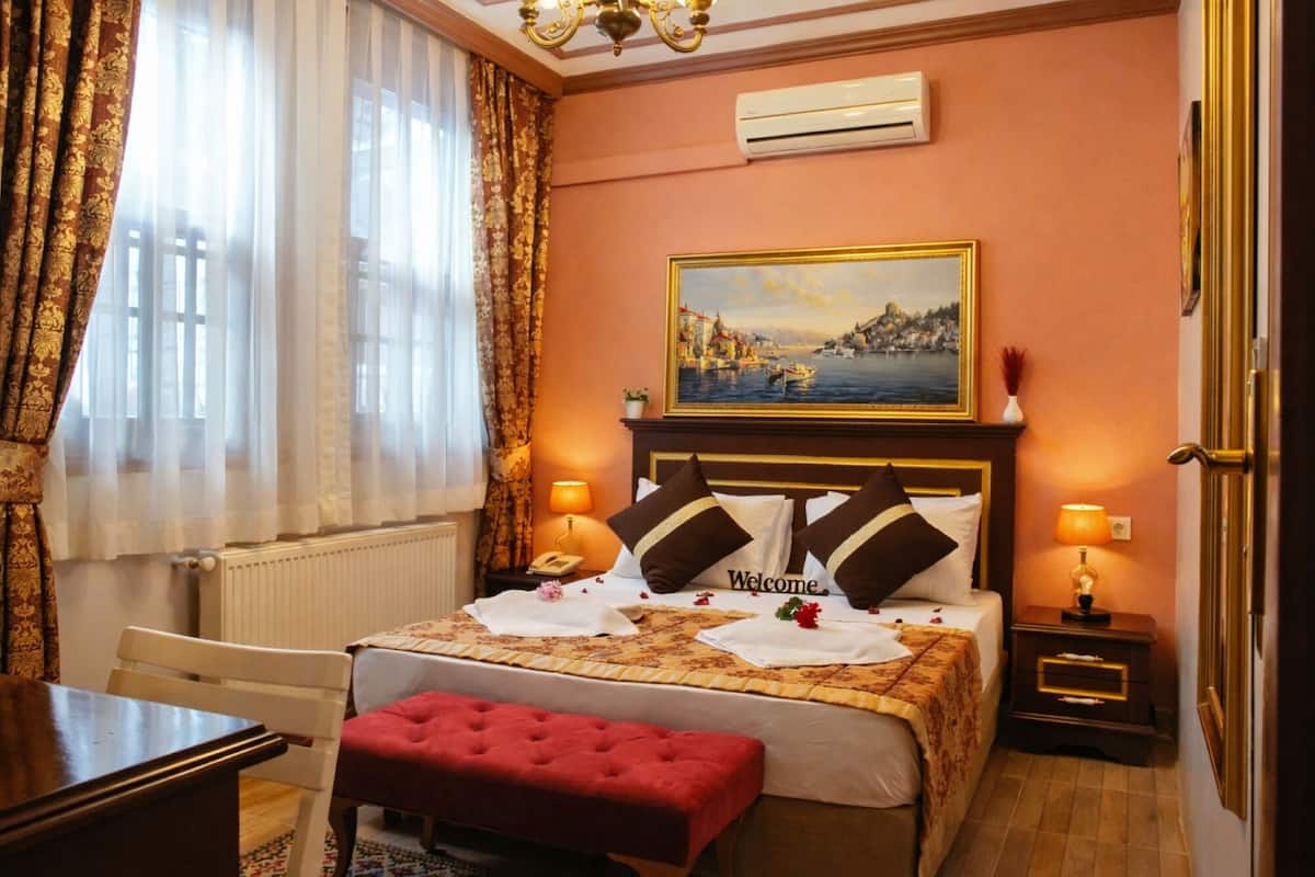 Quarto de hotel com cama, quadro, escrivaninha e cadeira.