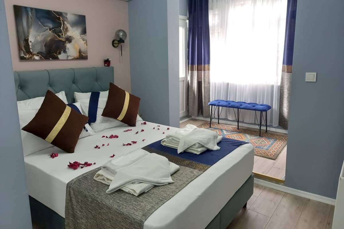 Uma cama bem arrumada com travesseiros, uma mesa de cabeceira e um ar condicionado fixado na parede.