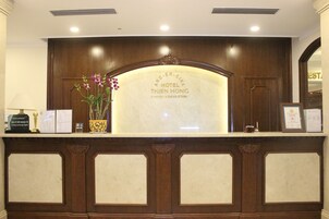 Balcão de recepção de hotel com tampo de mármore e painéis de madeira.