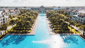 Um resort com piscina central, palmeiras e edifícios do resort.