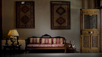 Um quarto com sofá, luminária, dois painéis decorativos e um armário de madeira.