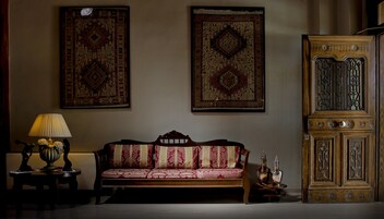 Um quarto com sofá, luminária, dois painéis decorativos e um armário de madeira.