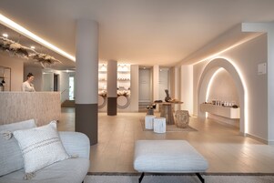 Um hall de hotel moderno com um sofá, um banco e uma área de recepção.
