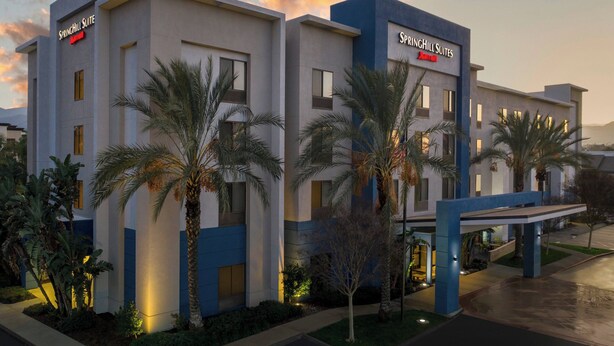 Um hotel moderno com o logotipo Marriott, apresentando uma estrutura de dois andares, palmeiras e uma entrada coberta.