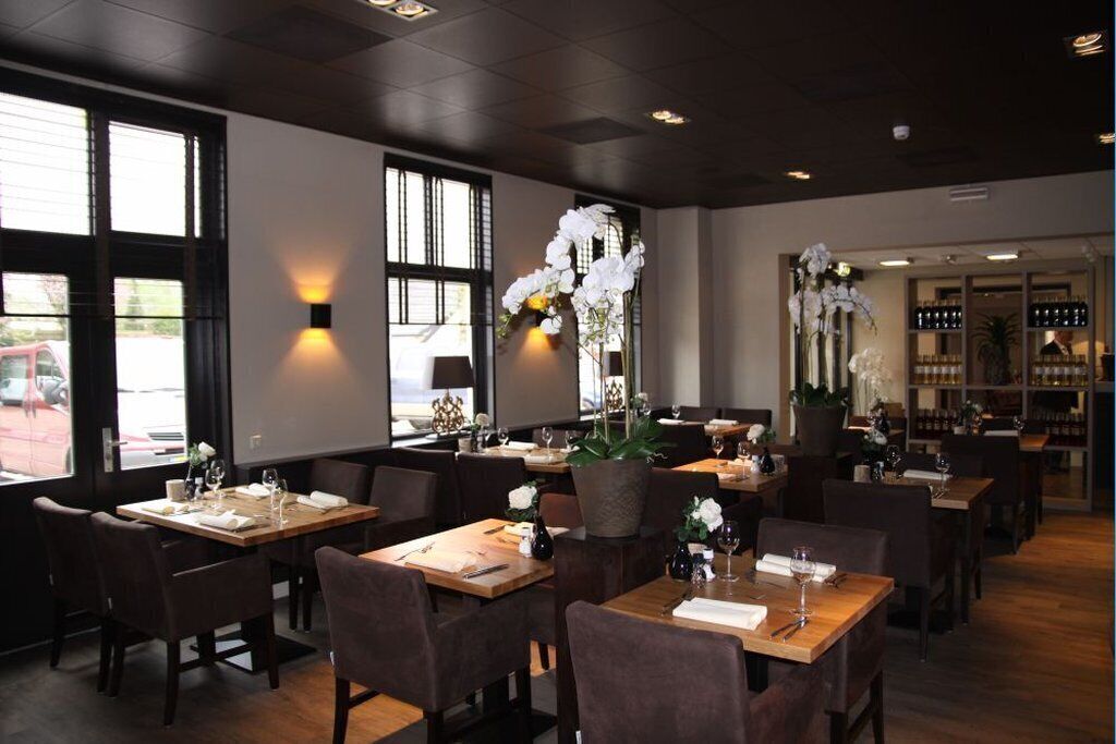 Um restaurante com várias mesas, cadeiras e um bar com prateleiras cheias de garrafas.
