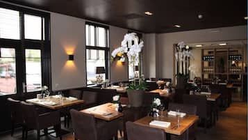Um restaurante com várias mesas, cadeiras e um bar com prateleiras cheias de garrafas.