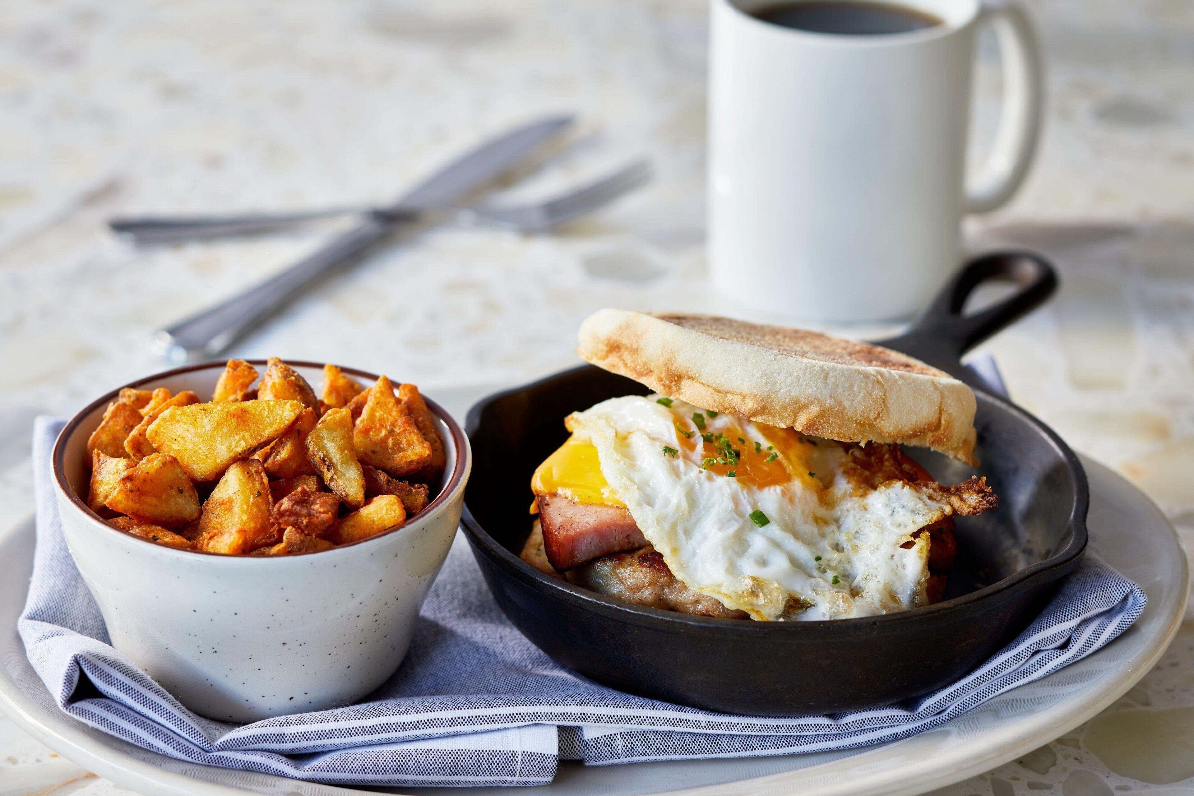 Prato de café da manhã com hash browns, ovo frito e uma fatia de torrada.