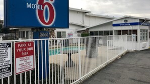 Placa de motel com área de piscina e estacionamento cercado.