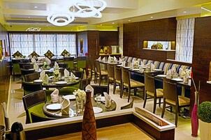 Restaurante moderno com várias áreas de refeição, incluindo um bar e um espaço de estar com pé direito alto e decoração contemporânea.