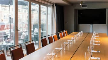 Uma sala de conferências com uma mesa comprida, cadeiras e copos.