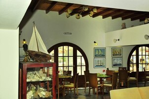 Uma sala de jantar com mobiliário de madeira, grandes janelas em arco e decoração temática náutica.