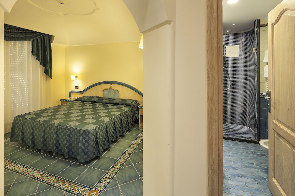 Um quarto com uma cama, uma mesa de cabeceira e uma luminária na parede.