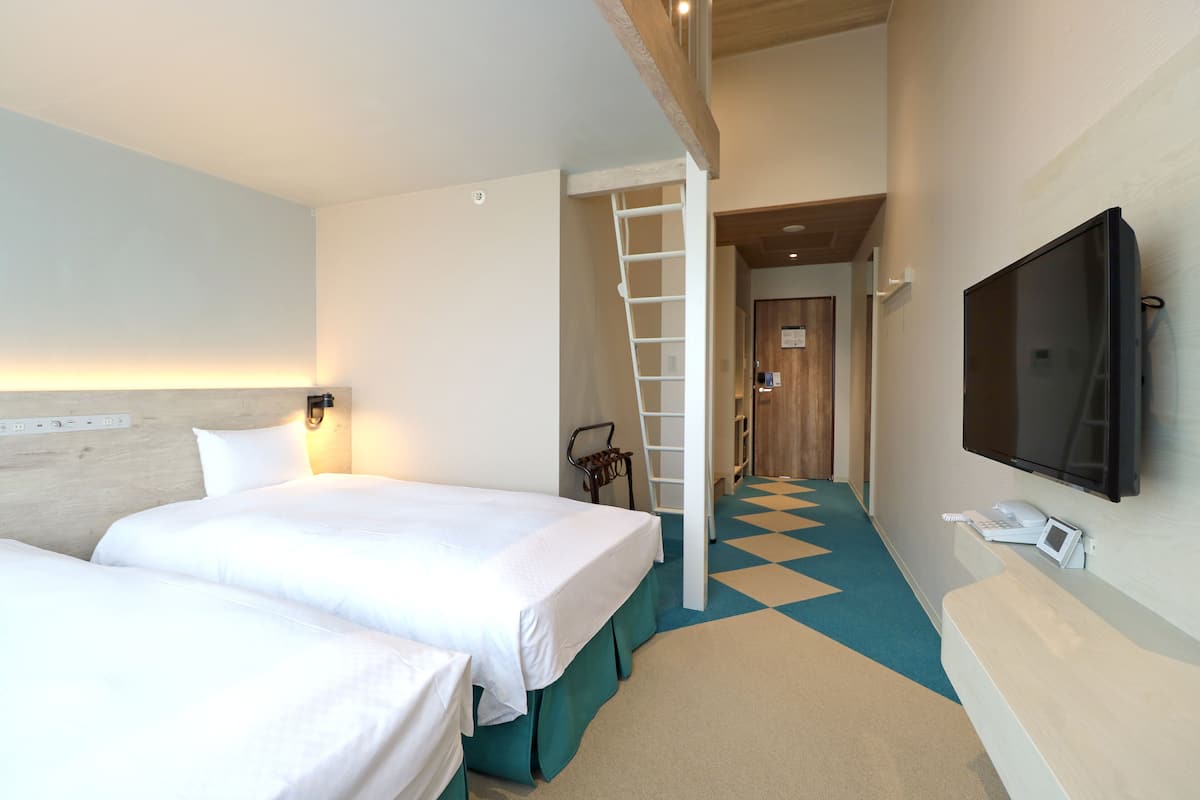 Quarto de hotel com duas camas, televisão, telefone e balcão de recepção.