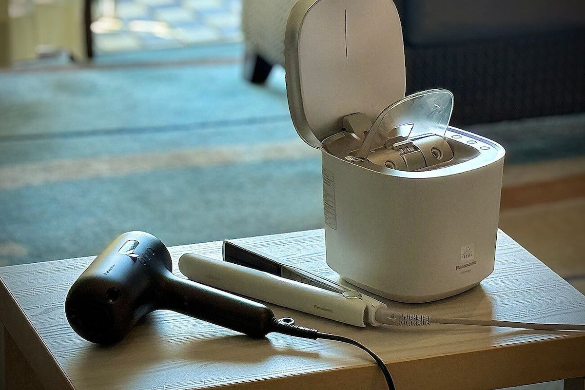 Um secador de cabelo e um aparelho portátil sobre uma mesa de madeira.