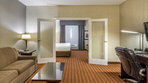Quarto de hotel com uma cama, uma escrivaninha, uma cadeira, um abajur e um sofá.