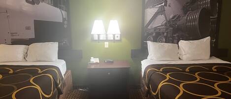Quarto de hotel com duas camas, uma mesinha de cabeceira, telefone e duas luminárias fixadas na parede.