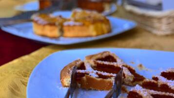 Um prato com uma sobremesa, possivelmente uma torta ou pastel, sobre uma mesa com toalha de mesa estampada.