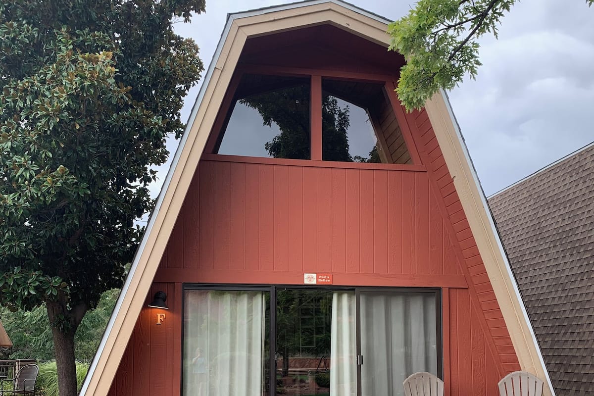 Um edifício triangular com fachada vermelha e entrada de vidro. Há duas cadeiras Adirondack lá fora.