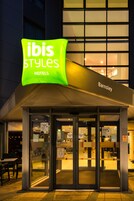 Entrada de hotel com uma placa de neon para 'Ibis Styles Hotels' e o nome 'Barnsley' sobre as portas.