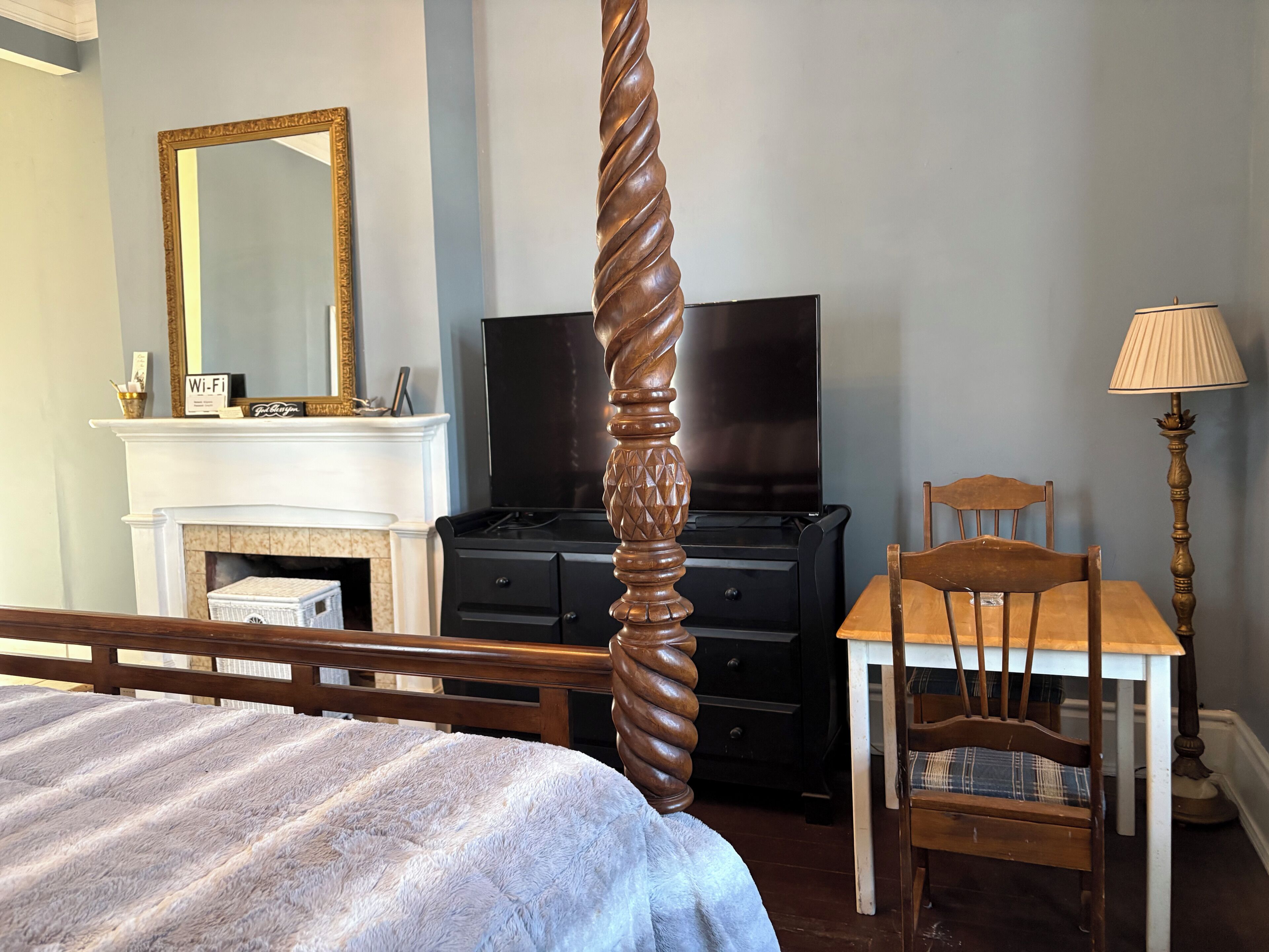 Quarto com cama, televisão, lareira, escrivaninha e cadeira.