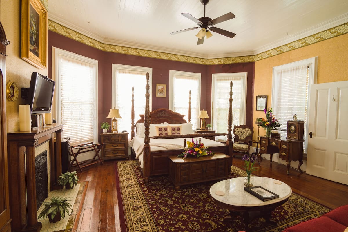 Um quarto tradicional com uma cama de dossel, uma televisão e uma mesa de centro redonda com um vaso.