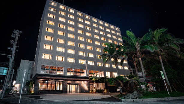 Um hotel com vários andares, janelas iluminadas e entrada bem iluminada.