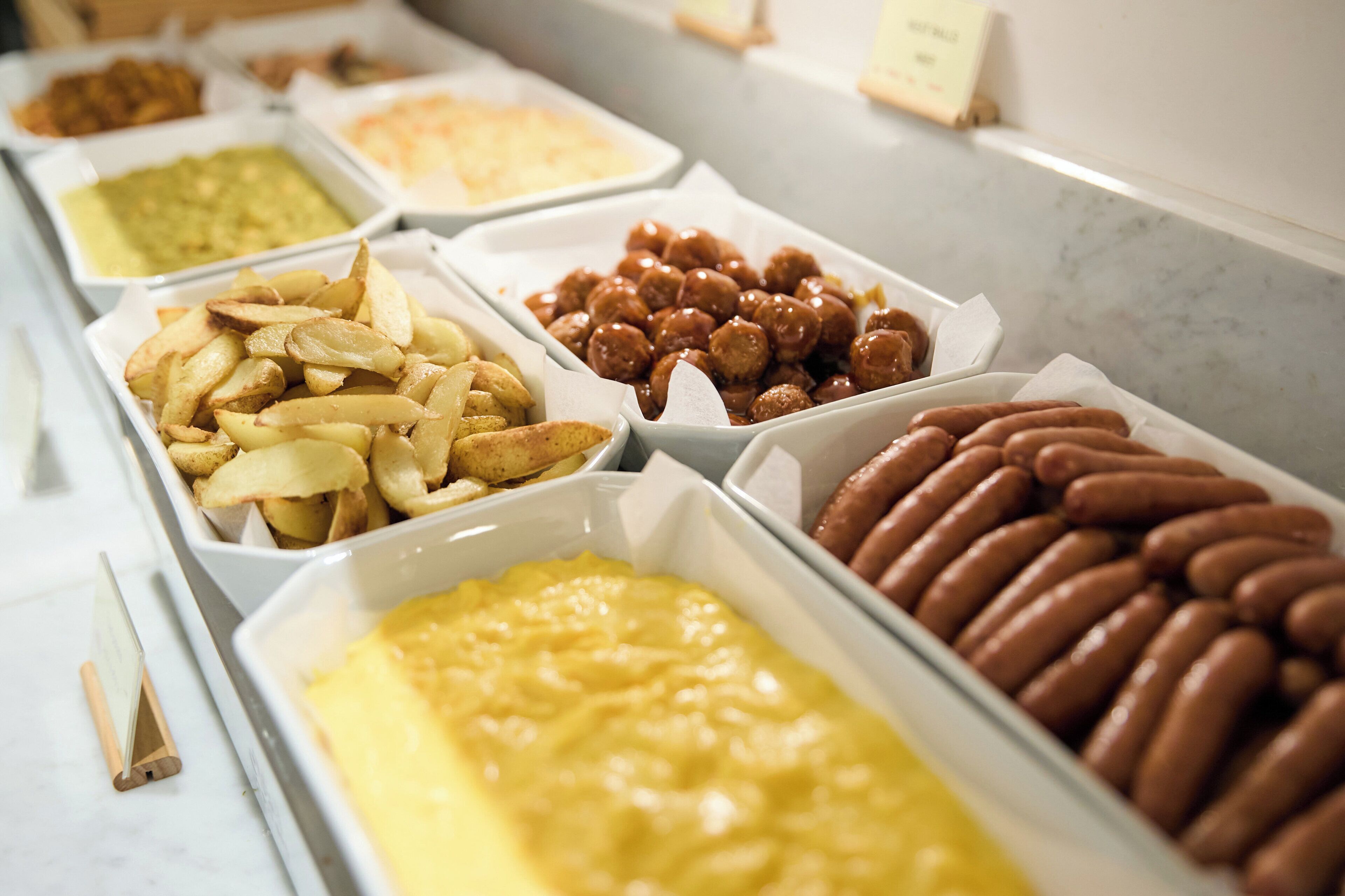Buffet com diversos pratos, incluindo batatas fritas, salsichas e macarrão com queijo.