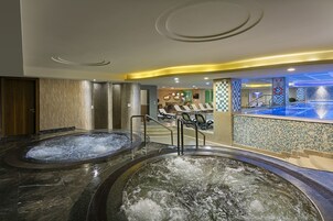 Área de spa com duas banheiras de hidromassagem e uma piscina.