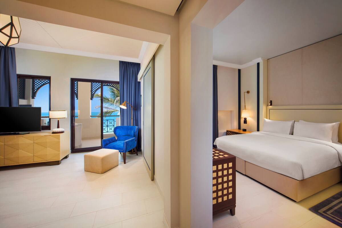 Quarto de hotel com cama, televisão, escrivaninha e cadeira.