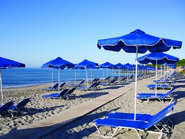 Na praia, areia branca, espreguiçadeiras, guarda-sóis