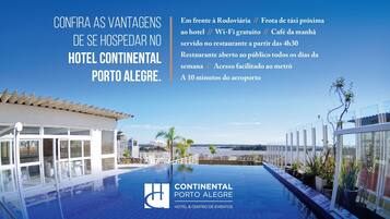Piscina de hotel com vista para a cidade e para um corpo de água.